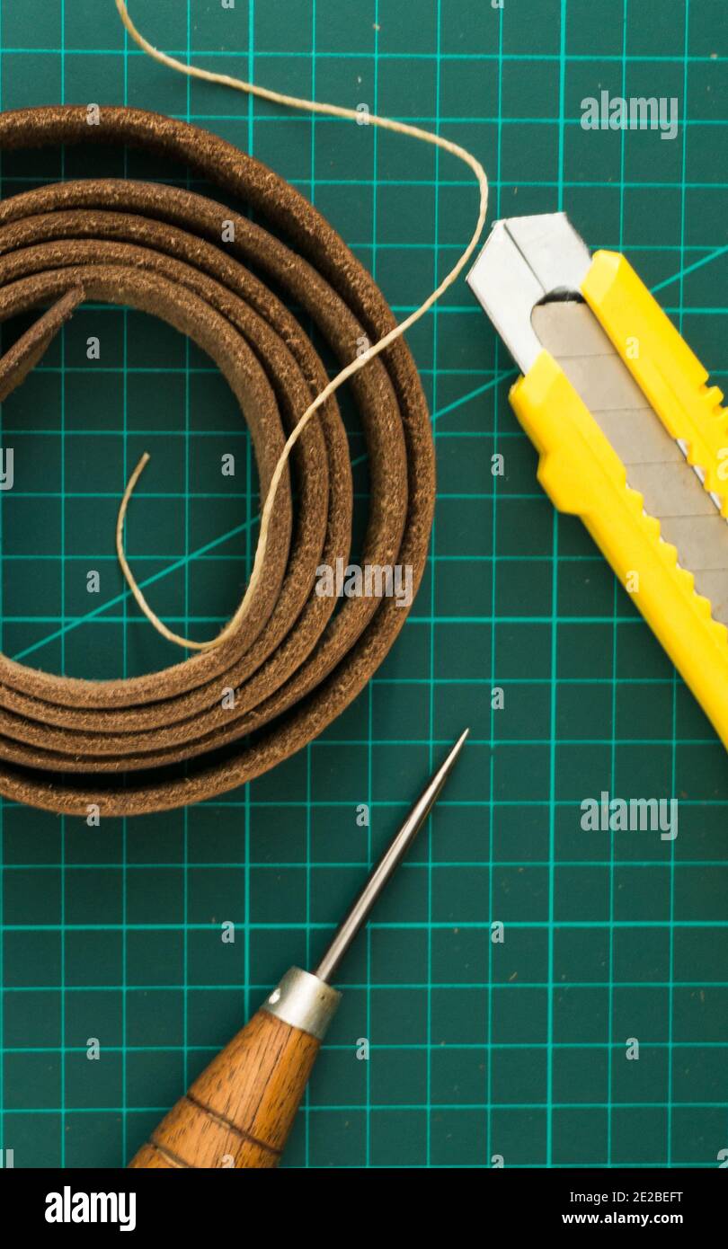 Vertical top view of leatherworker supplies on a craftsman's work table ...
