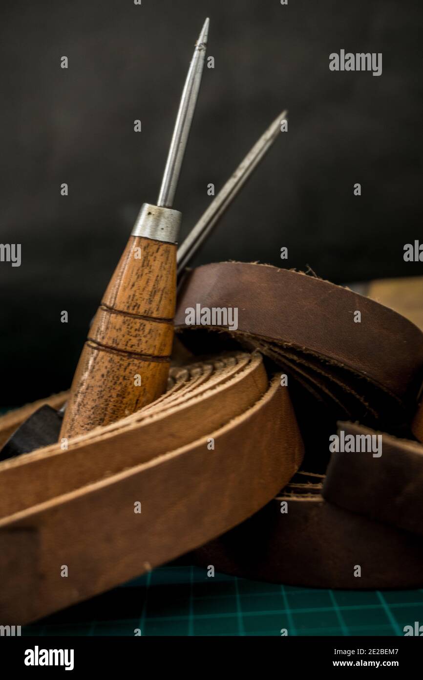 Vertical shot of a wooden stitching awl and genuine leather rolls on a ...