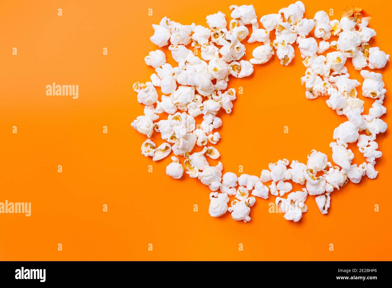 Scattered popcorn in the shape of heart on orange background. Time ...