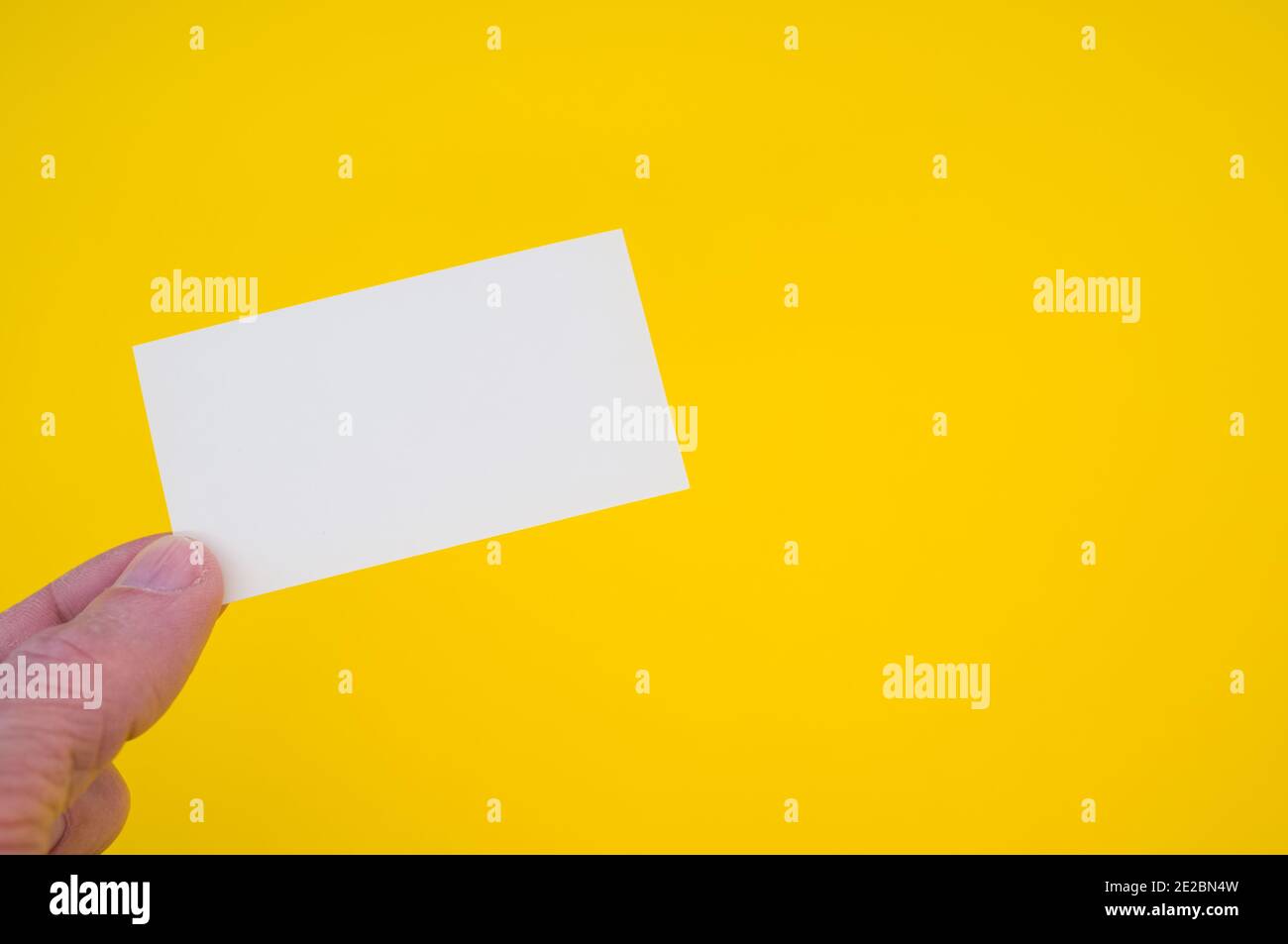 Closeup shot of a person holding a blank paper on a yellow background ...