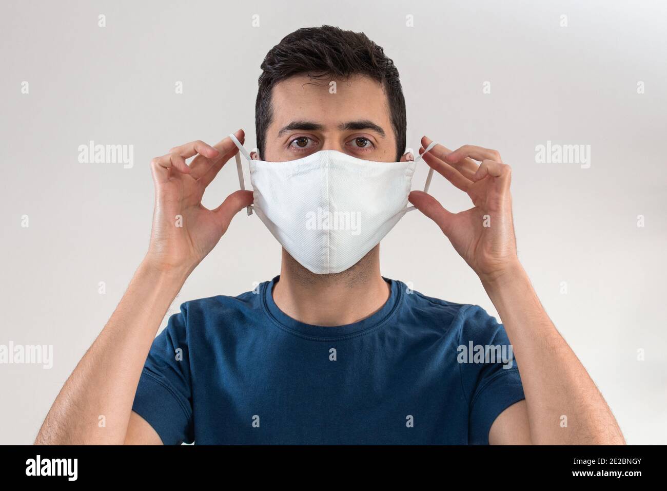 Young man putting on a mask to cover his mouth and nose Stock Photo - Alamy