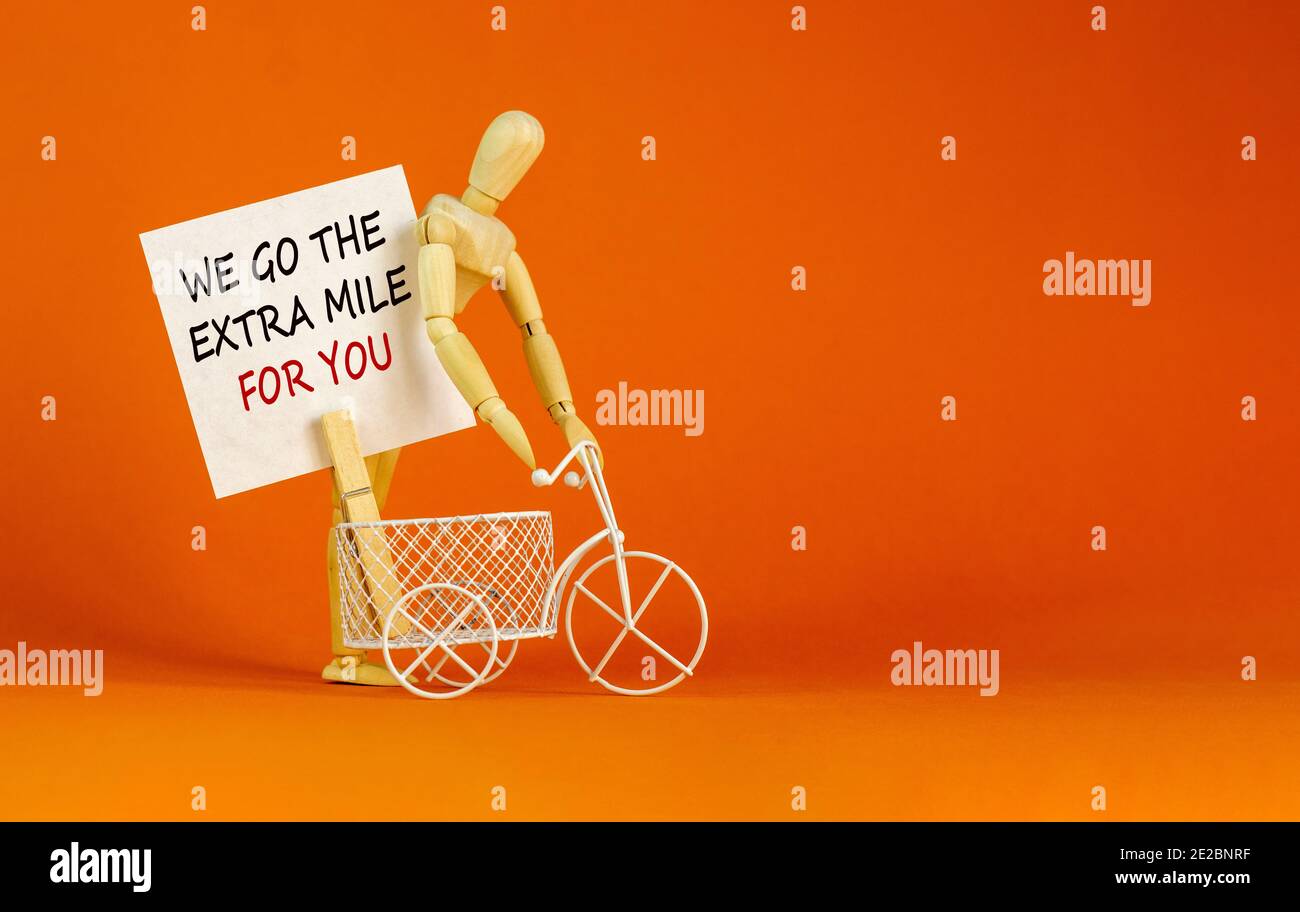 Go extra mile symbol. White sheet of paper. Words 'we go the extra mile ...