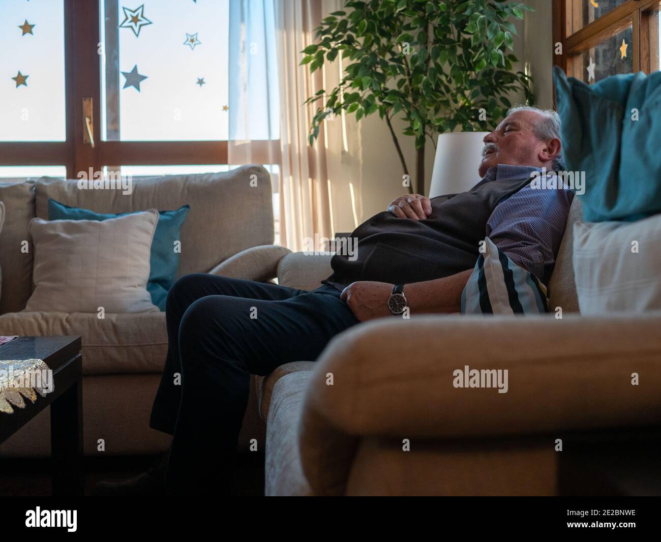 Tired elderly male fall asleep on a comfortable couch in the living ...