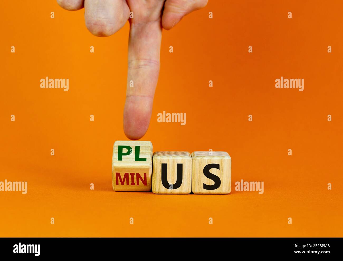 Plus or minus symbol. Businessman hand turns wooden cubes and changes ...