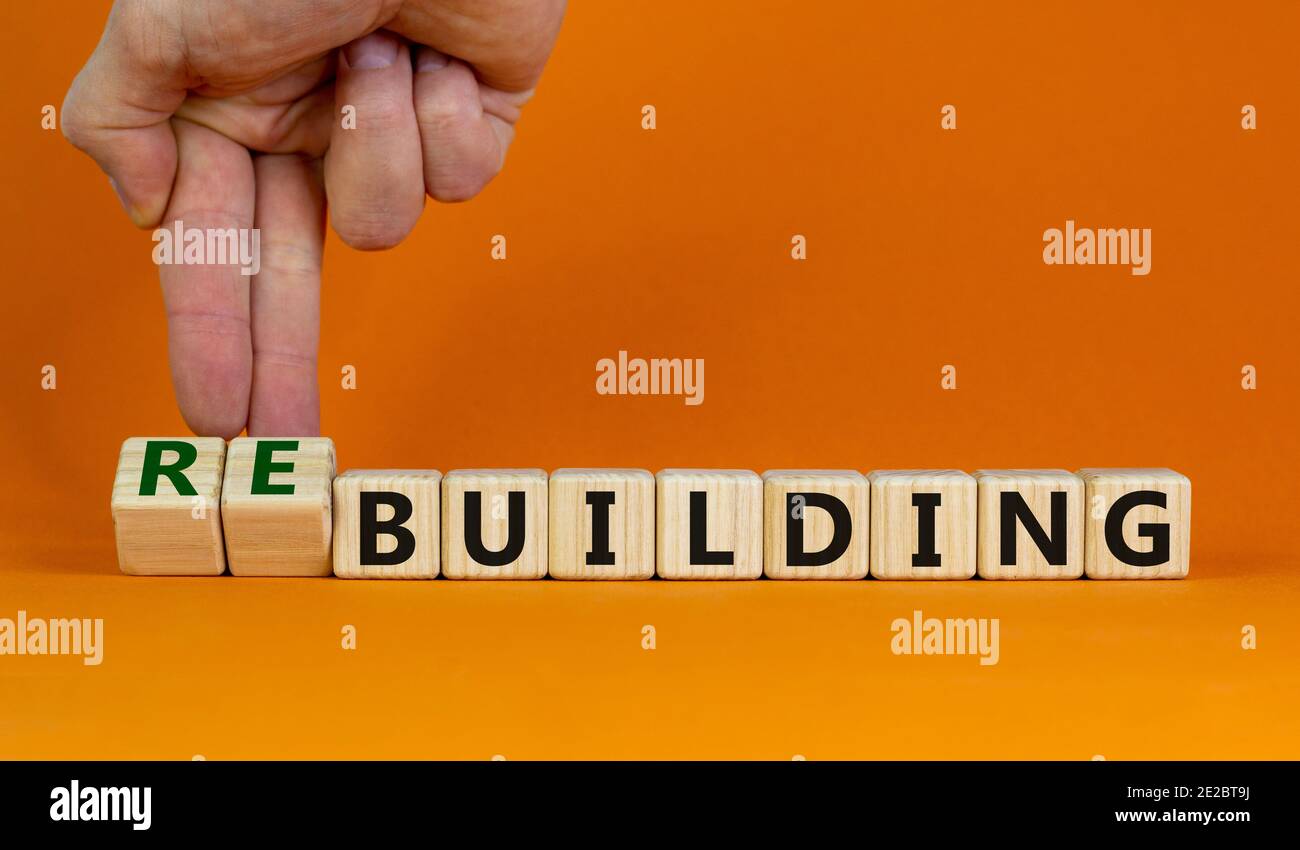 Rebuilding symbol. Male hand turns wooden cubes and changes words ...