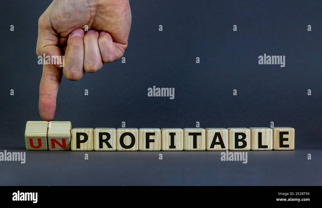 Profitable or unprofitable symbol. Businessman hand turns cubes and ...