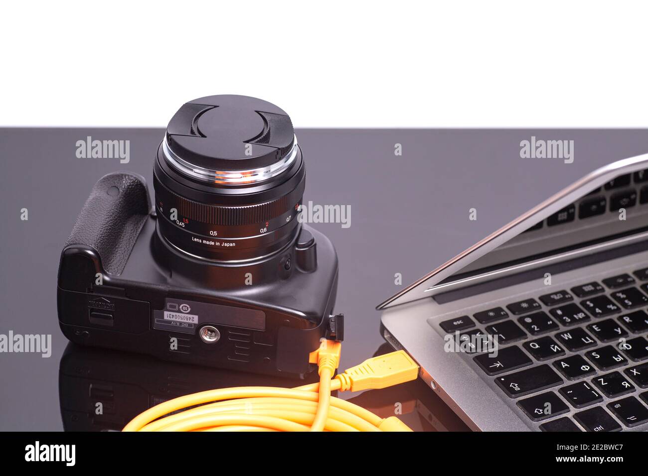 Digital photo camera connected to laptop with orange rolled cable Stock ...