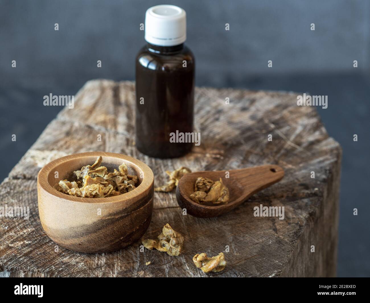 Vial of propolis, blooming flowers, wooden bowl and spon of propolis ...