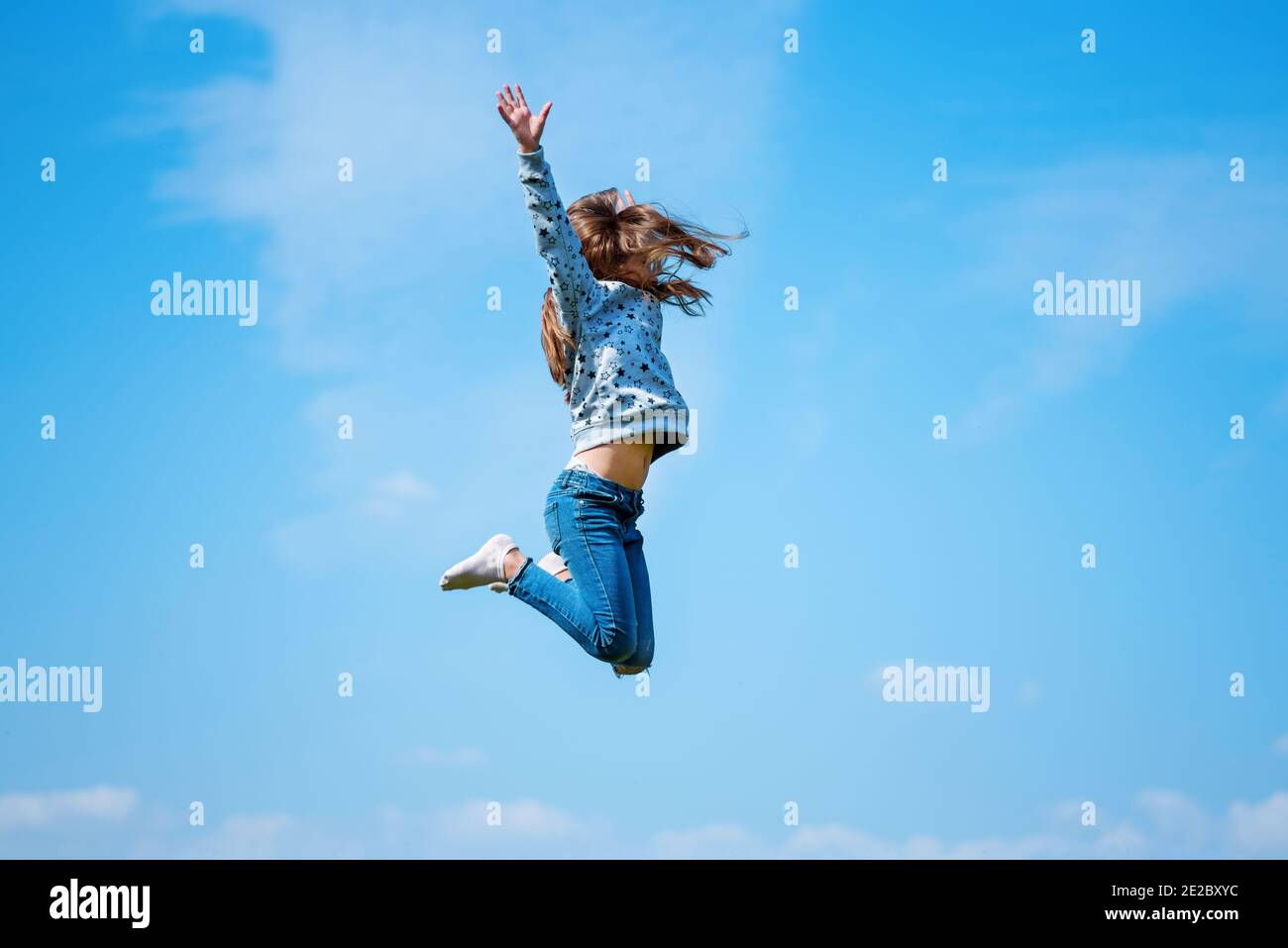 Little girl jumping in nature on a background of blue sky. Happy ...