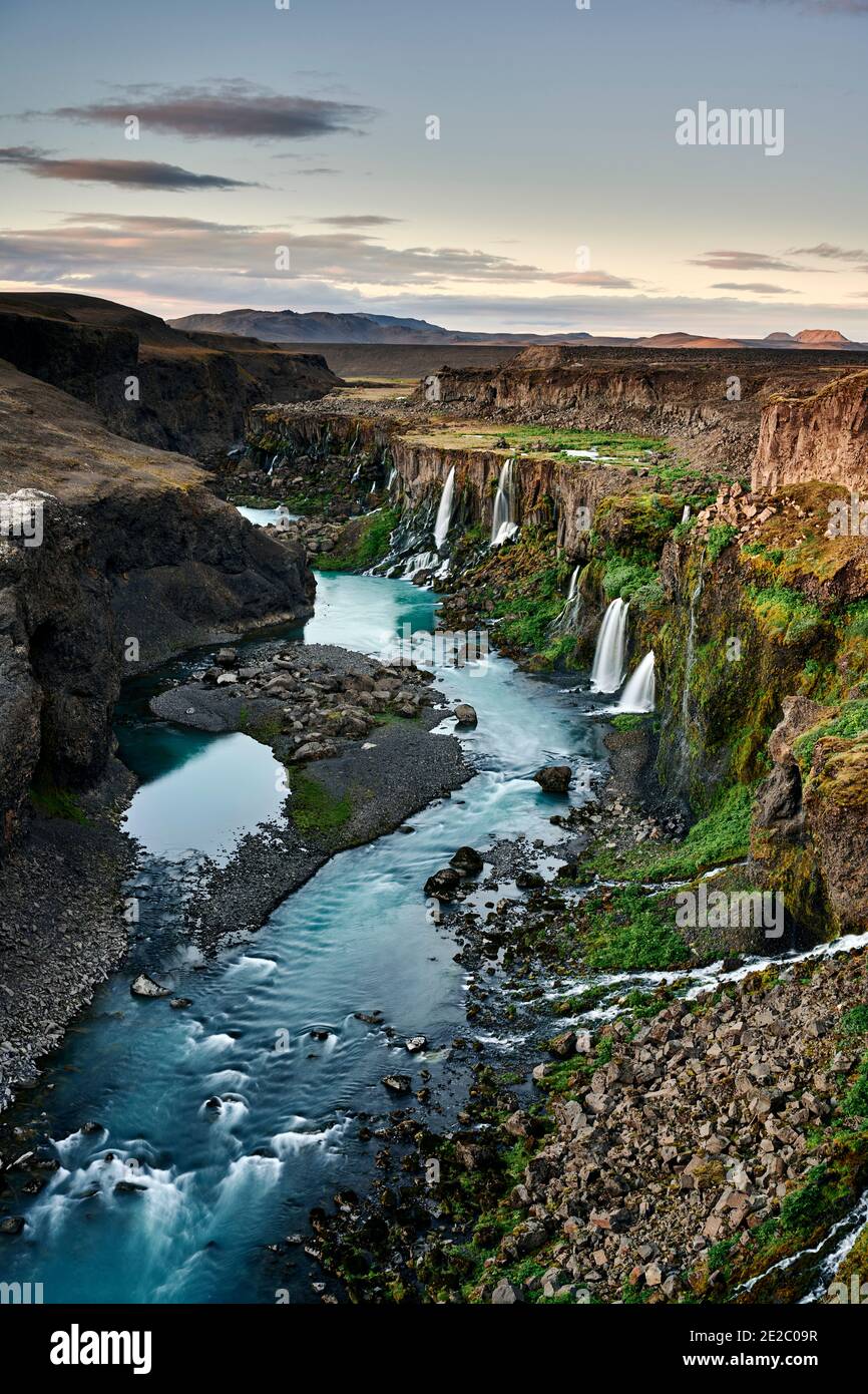 Clean waterfalls and river located in picturesque canyon against cloudy ...