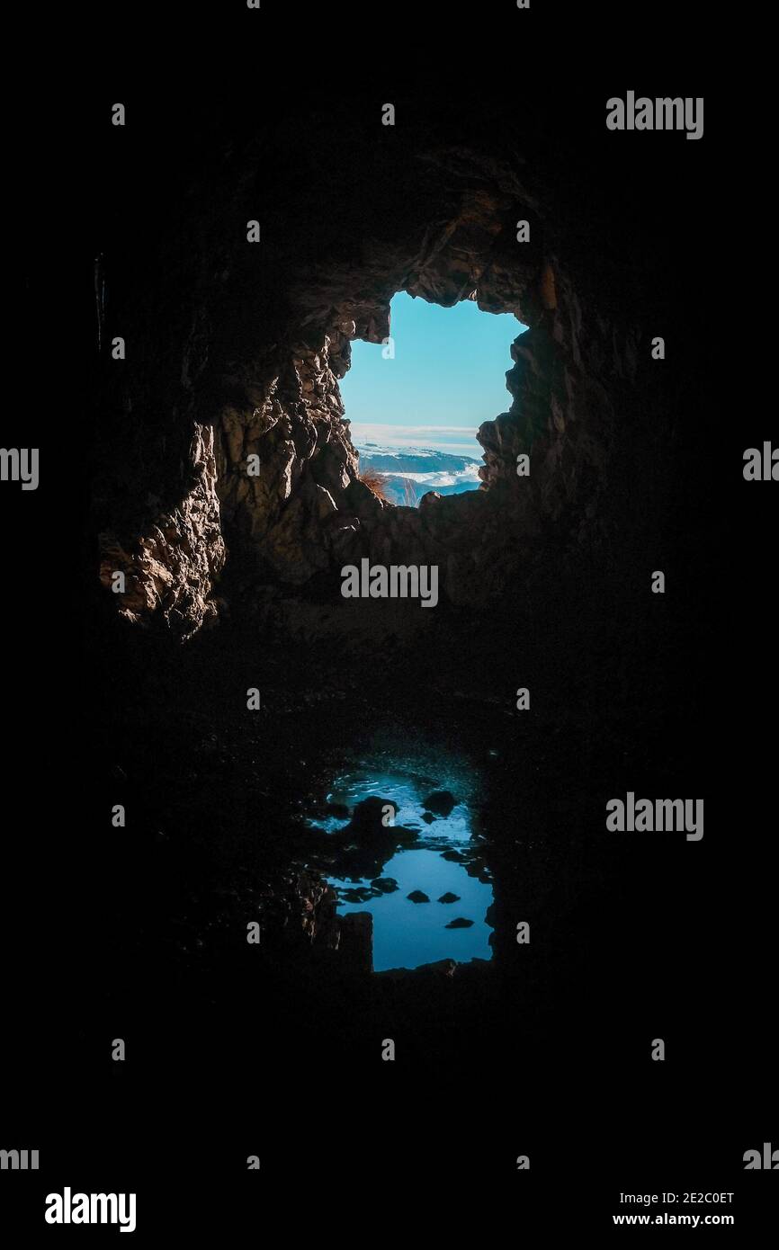 Vertical shot of a stone cave entrance reflecting in water inside Stock ...