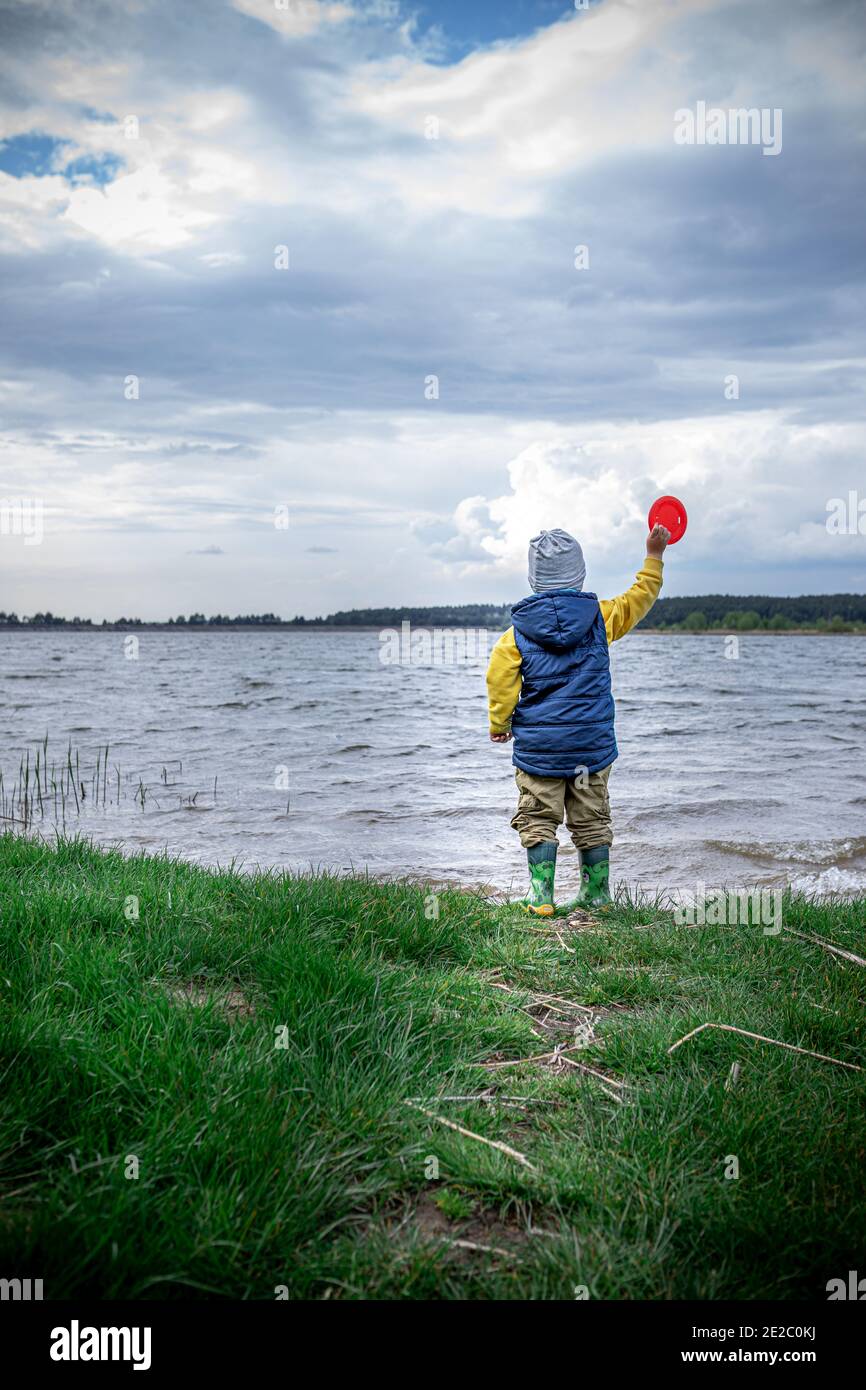 little kid throwing rocks in lake. rubber boots. copy space Stock Photo ...
