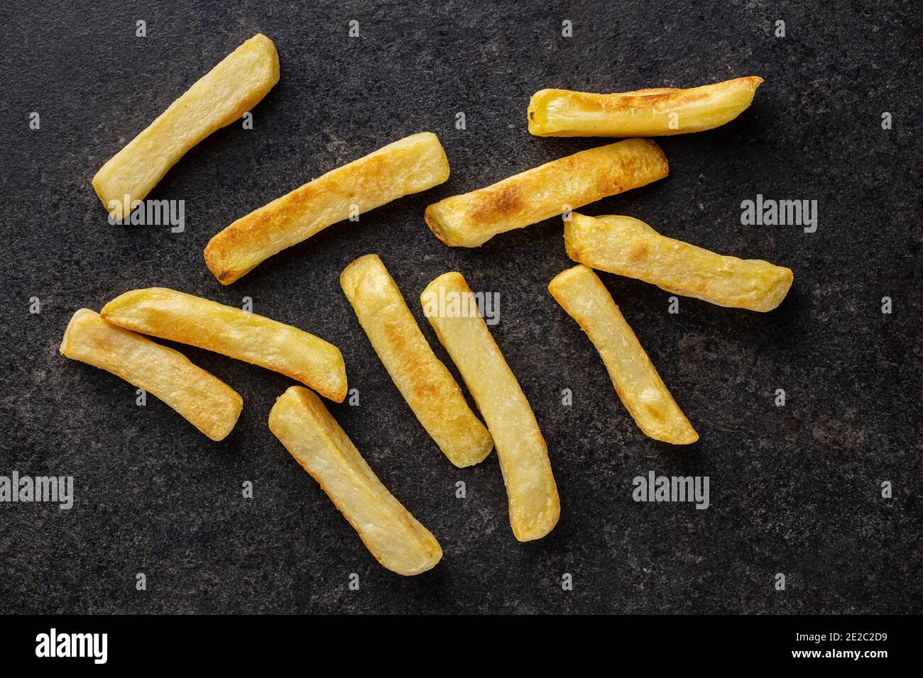 Big french fries. Fried potato chips on black table. Top view Stock ...
