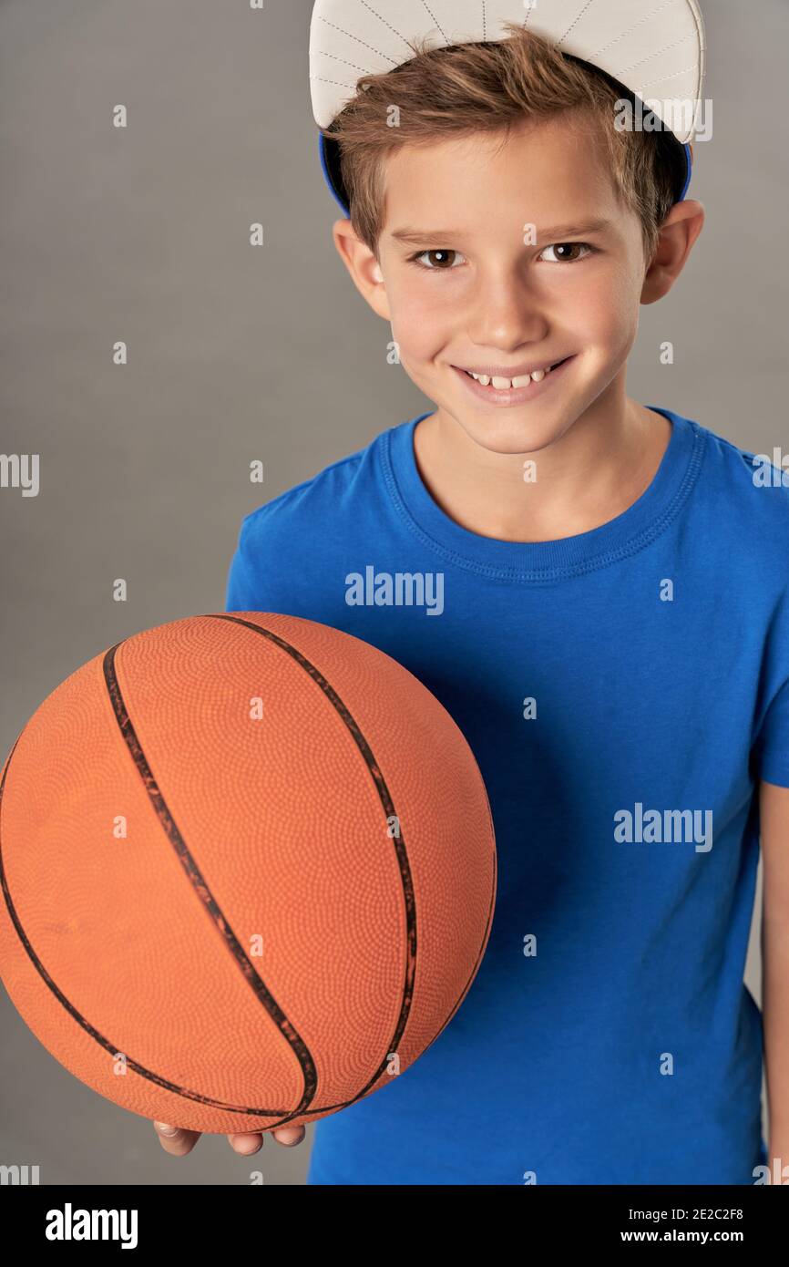 Adorable boy basketball player holding game ball and smiling while ...