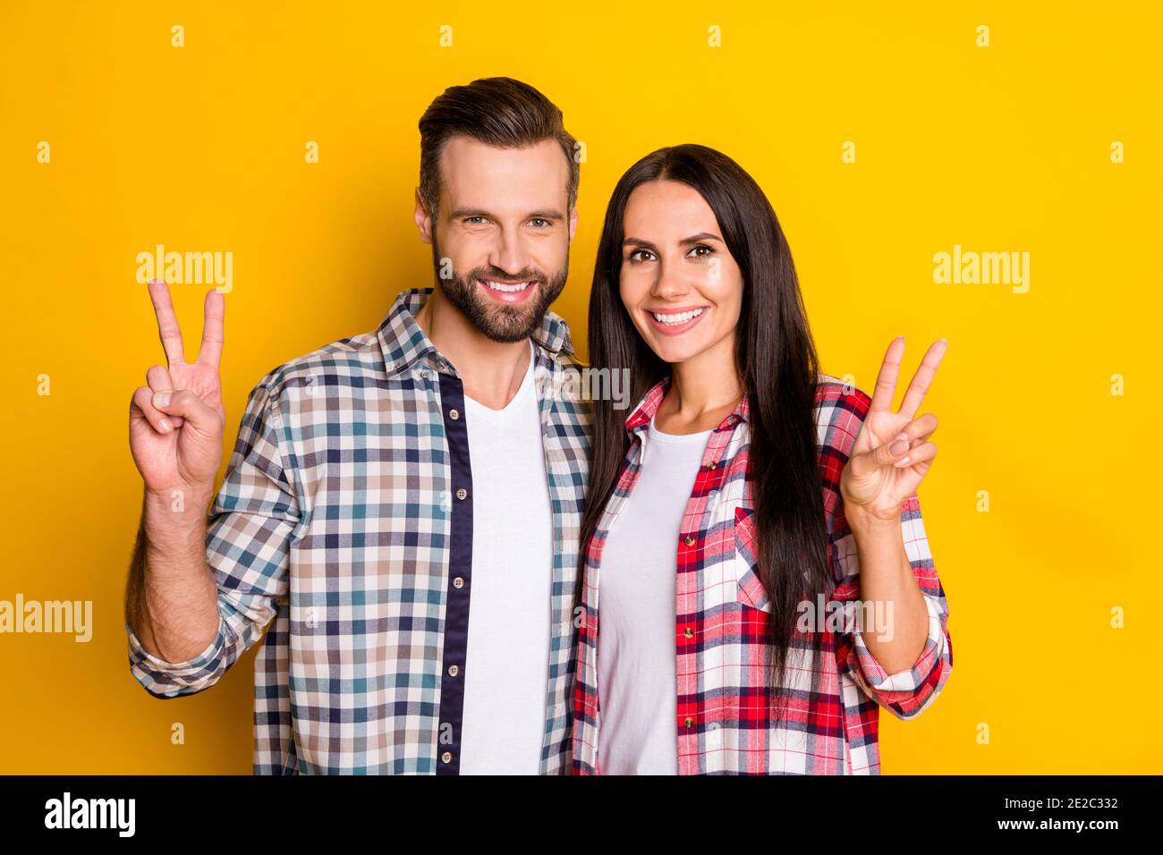 Portrait of two attractive cheerful people embracing showing v-sign ...