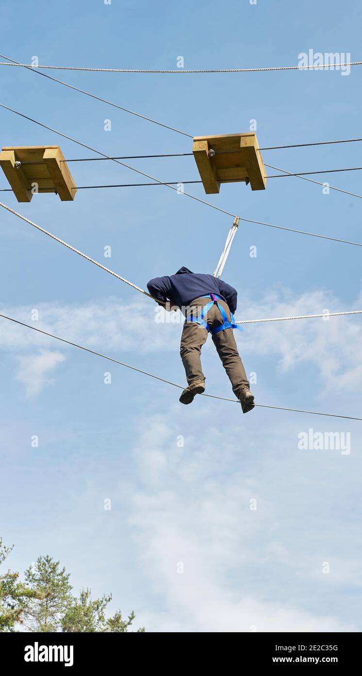 high ropes/challenge course. participant walking guide wire while ...