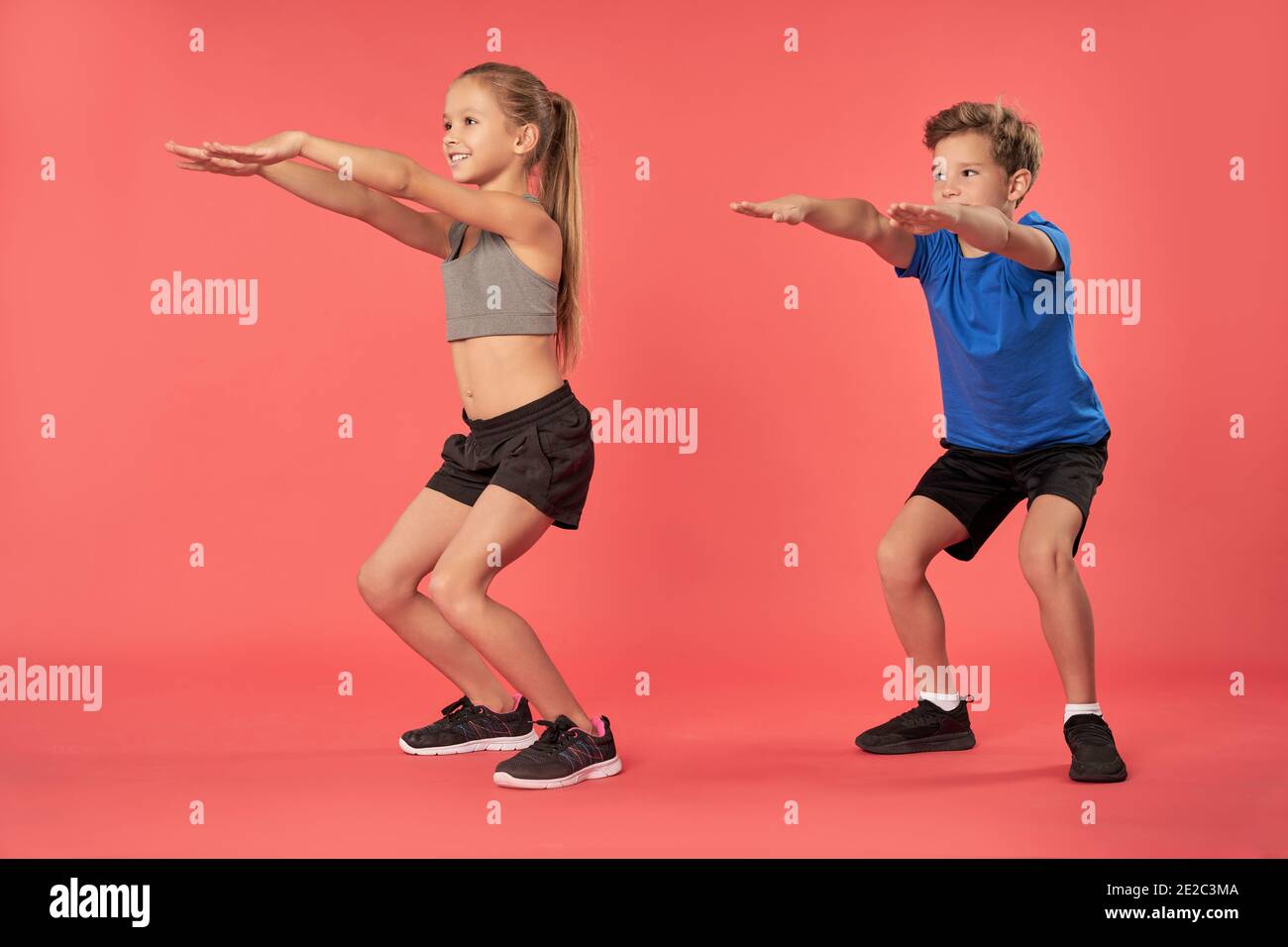 Cheerful sporty kids looking away and smiling while doing exercise ...