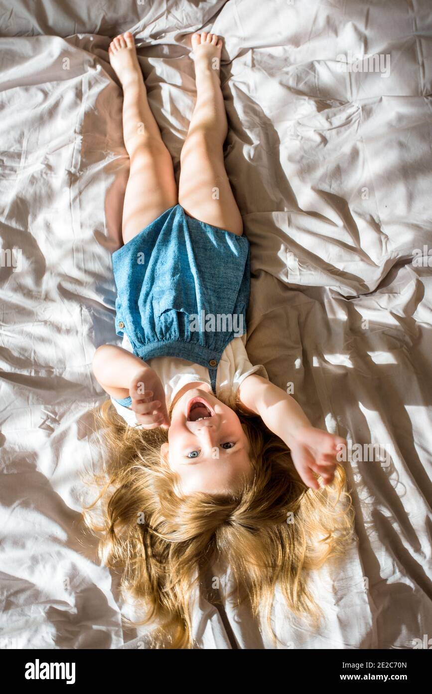 Cheerful baby laughing.A cheerful girl lies on the bed and screams with ... Cheerful baby laughing.A cheerful girl lies on the bed and screams with ...