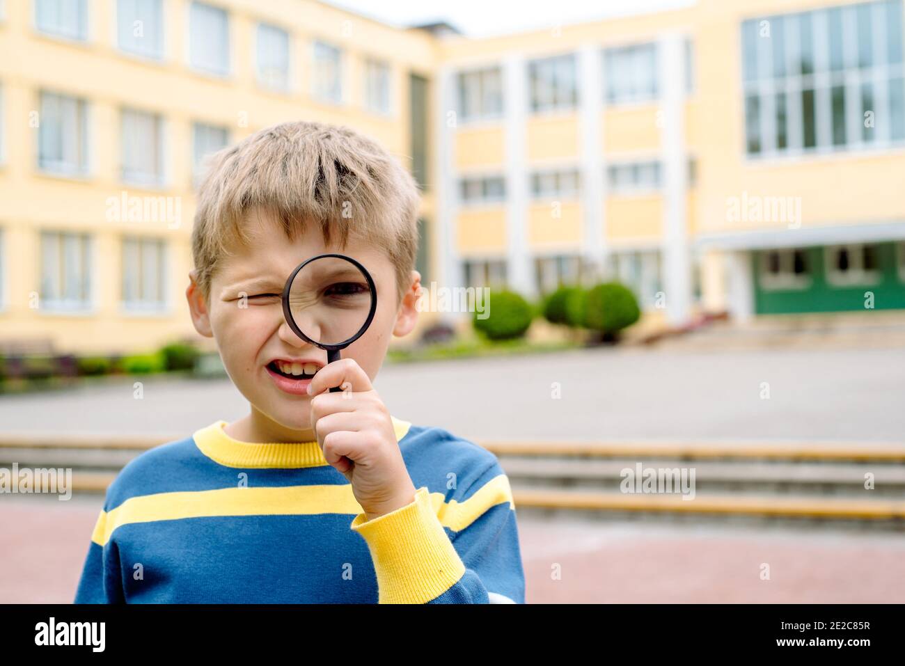 Curious surprised boy. One schoolboy with magnifier near his eye in the ...