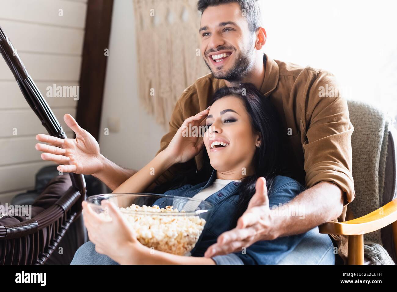 excited man pointing with hands while watching tv with girlfriend ...