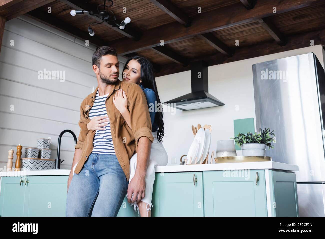 happy young woman sitting on kitchen counter and embracing boyfriend ...