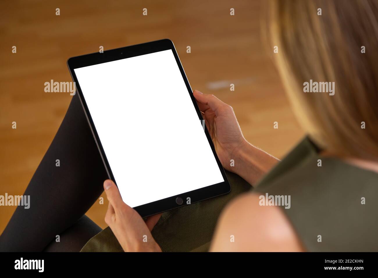 Attentive young woman holding tablet with white screen in vertical ...