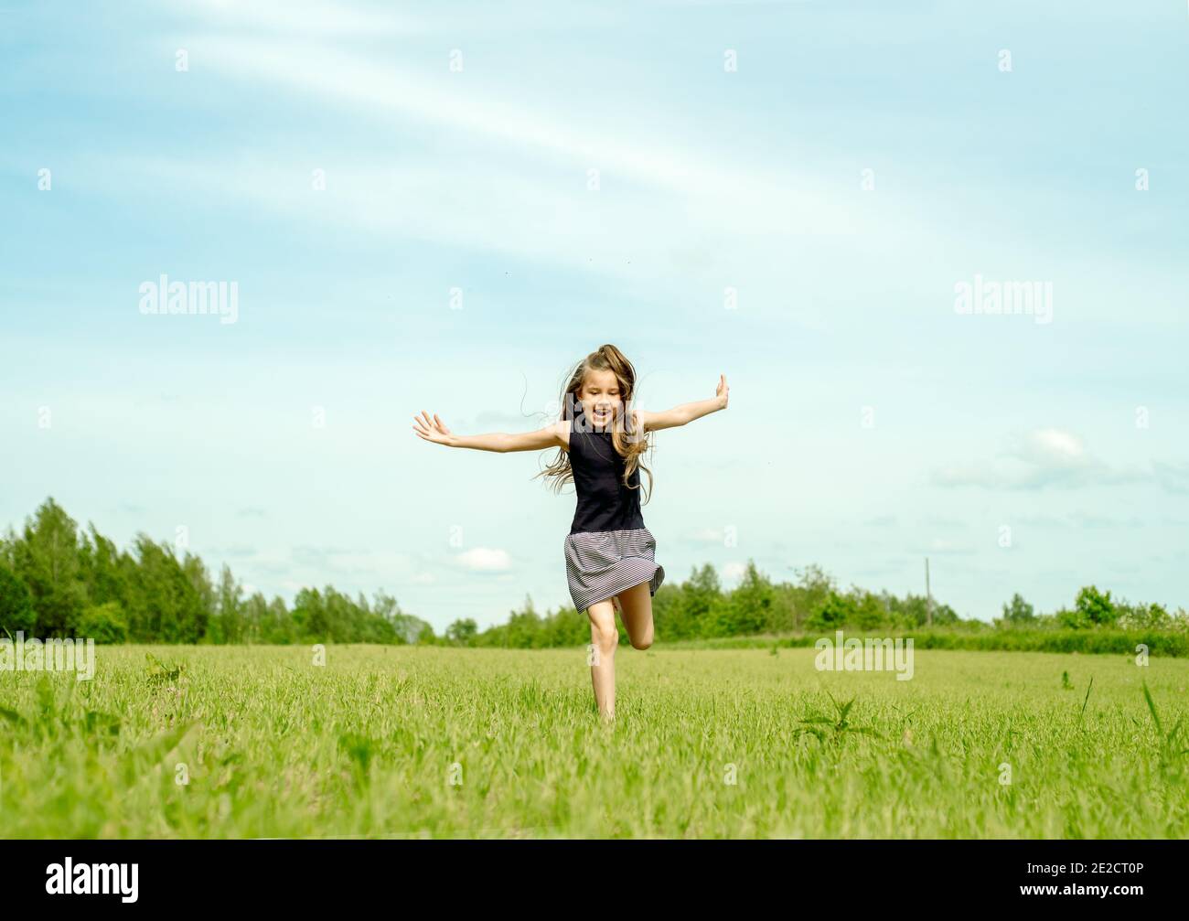 Kid girl jumping on the grass at spring.Summer field, horizon and sky ...