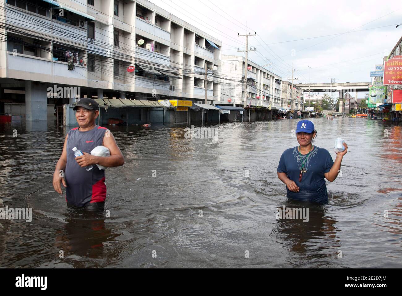 Flood victims make their way through a flooded neighborhood in Ban Mai ...