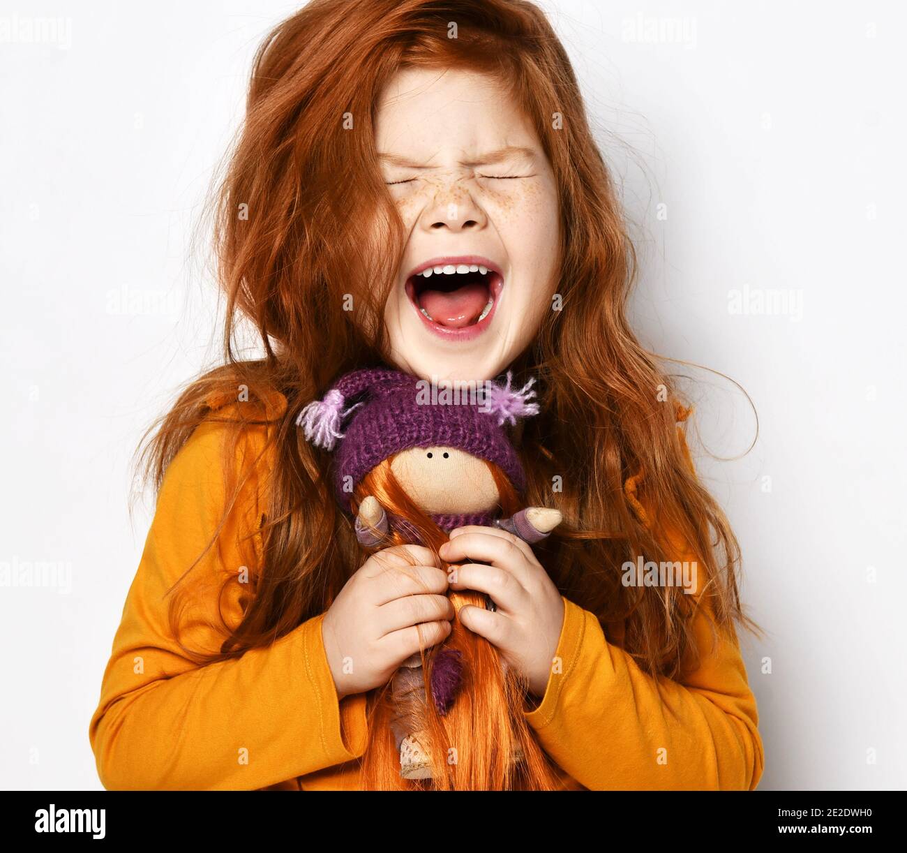 Cheerful small red haired girl in yellow comfortable longsleeve ...