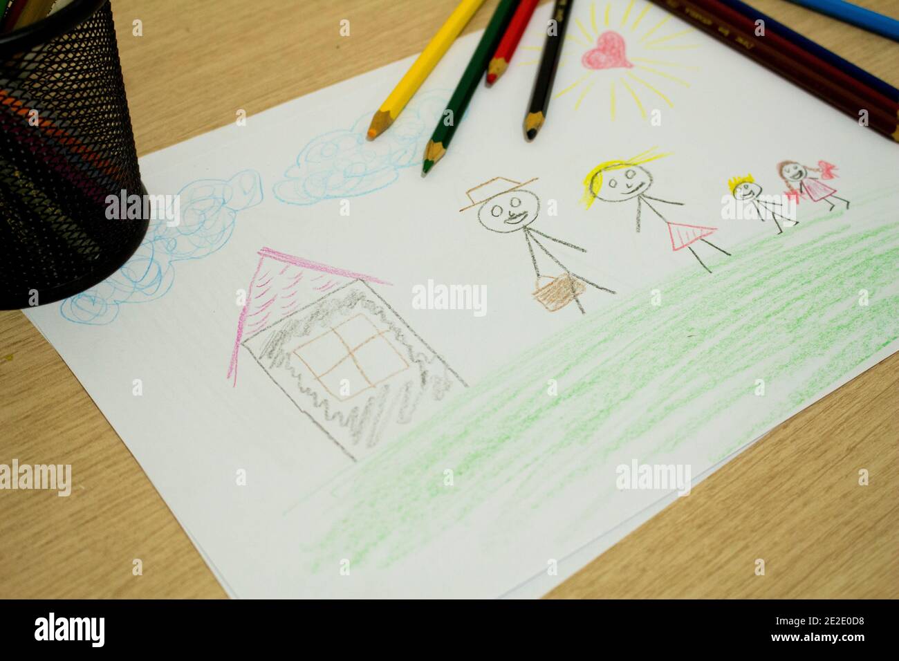 Colorful childlike drawing of a happy family with colored pencils aside ...