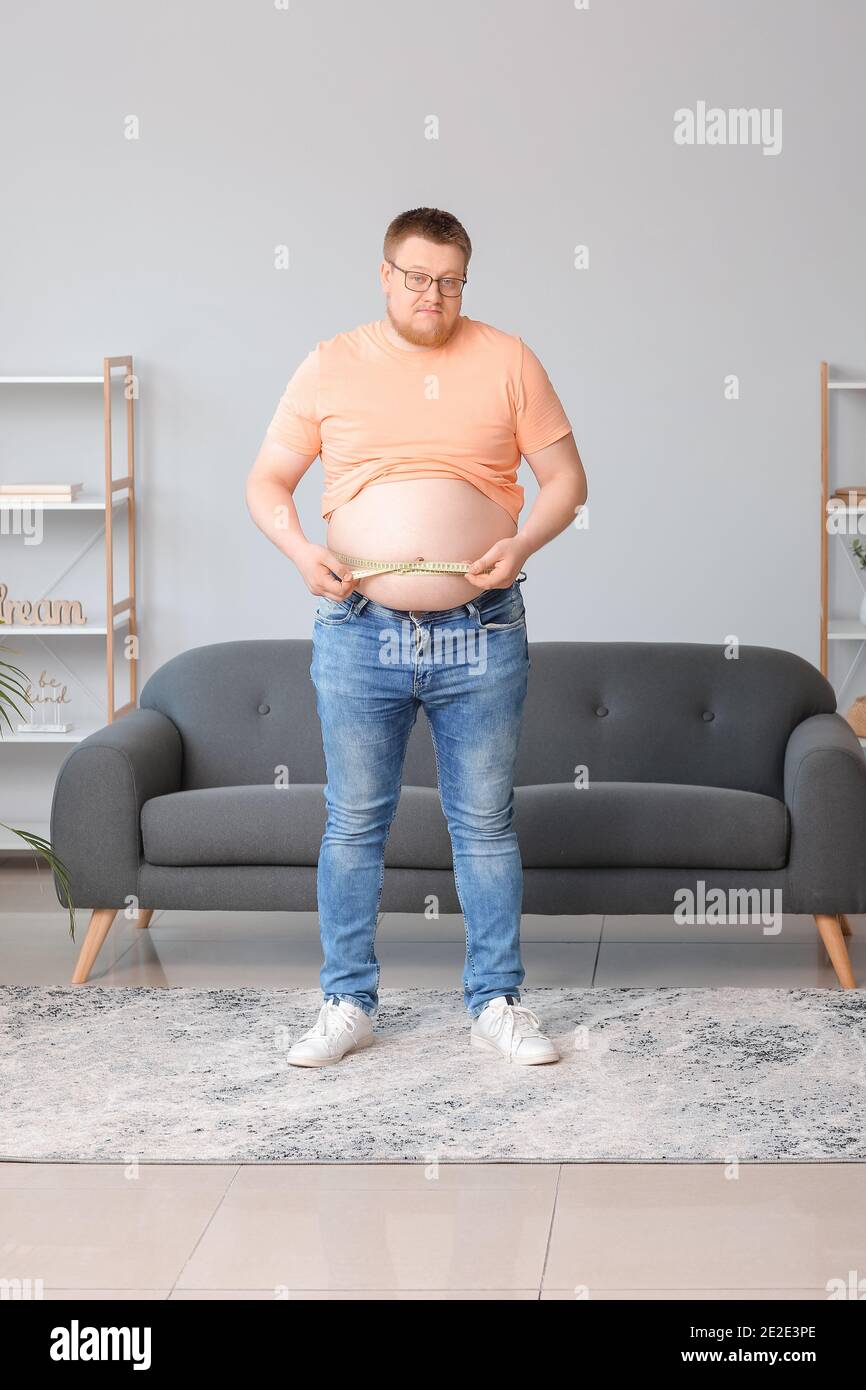 Sad overweight man with measuring tape at home. Weight loss concept ...