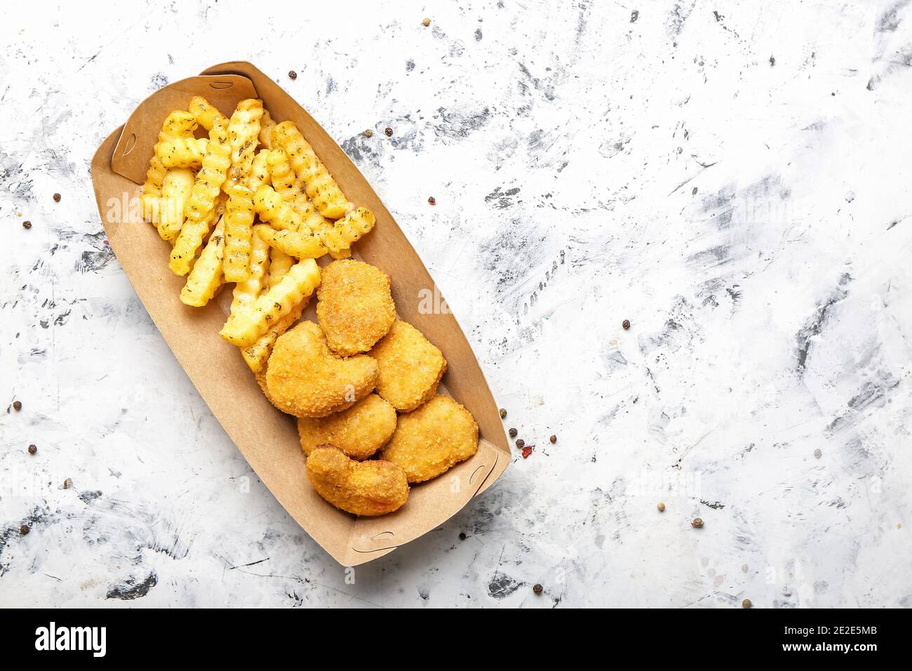 Tasty nuggets and french fries in paper box on light background Stock ...