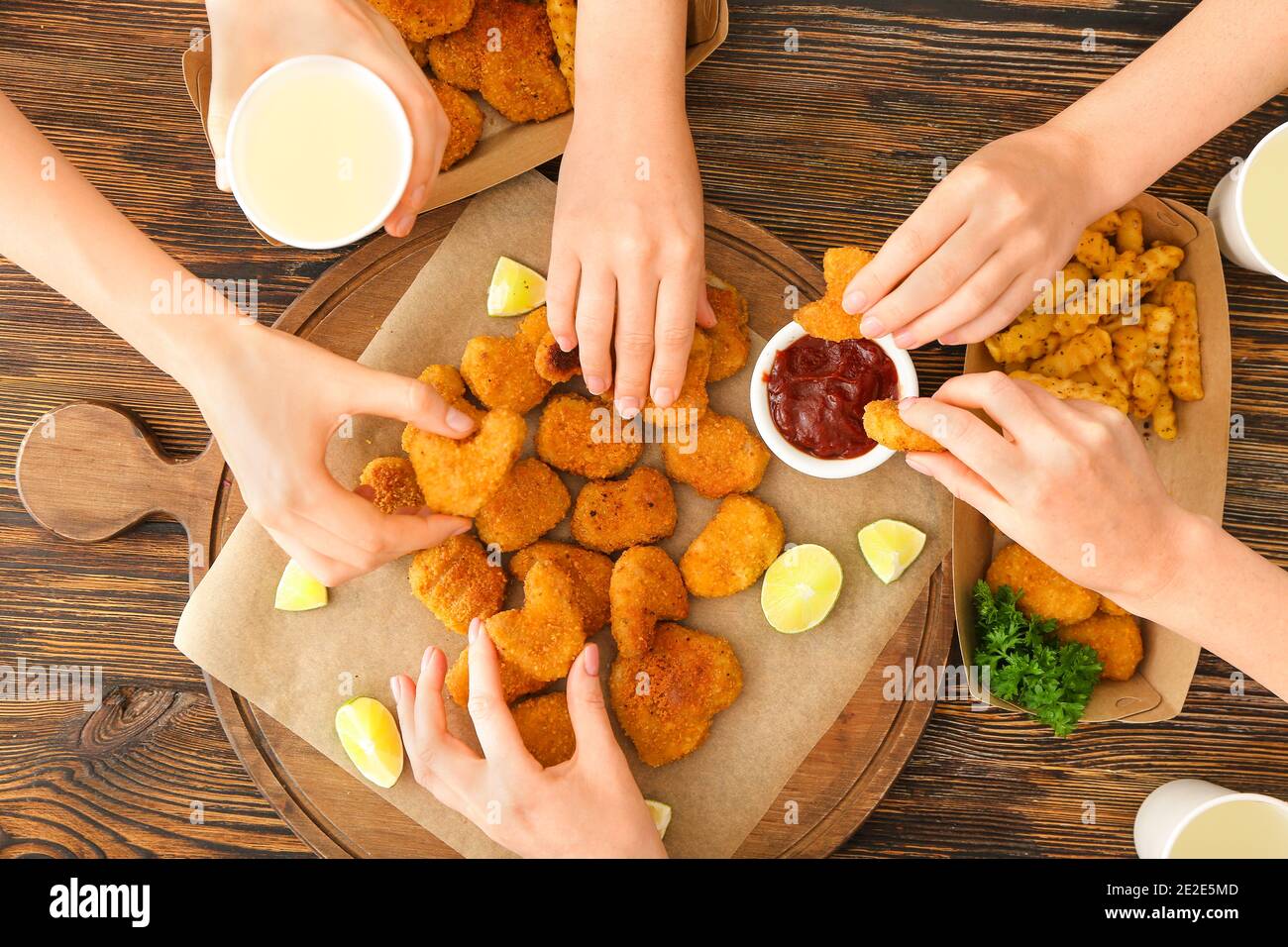 Group of friends eating tasty nuggets on wooden background Stock Photo ...