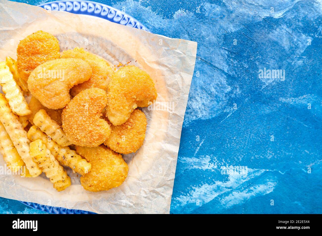 Tasty nuggets and french fries in plate on color background Stock Photo ...