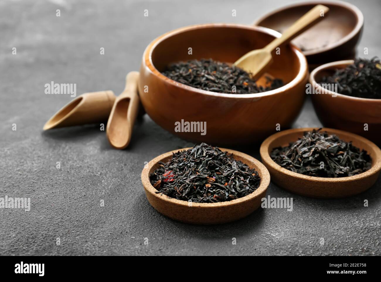 Dry black tea leaves in bowls and scoop on dark background Stock Photo ...