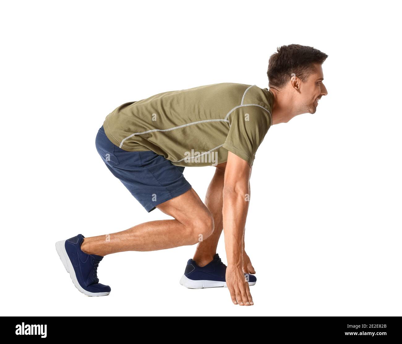 Sporty young man standing in crouch start position isolated on white ...
