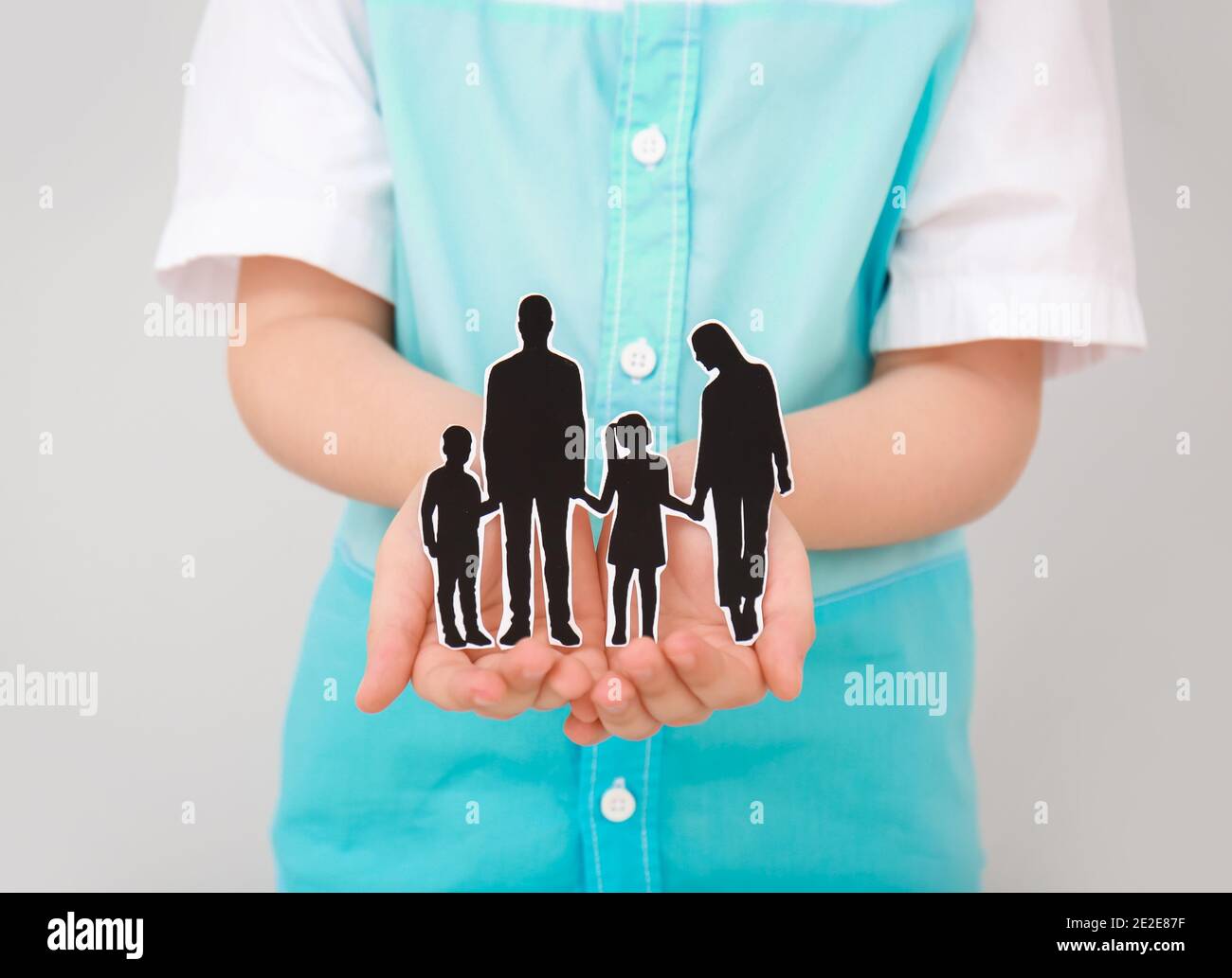 Child holding human figures on light background Stock Photo - Alamy