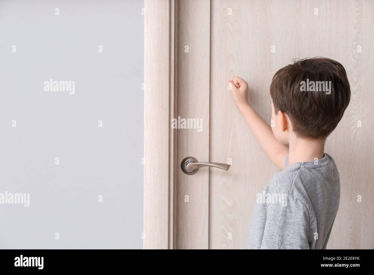 Little boy knocking at closed door Stock Photo - Alamy