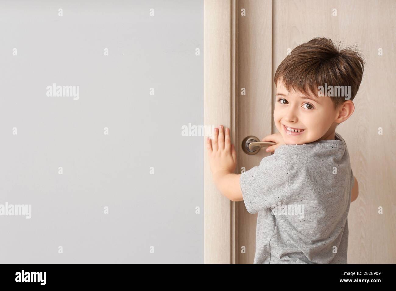 Cute little boy standing near closed door Stock Photo - Alamy