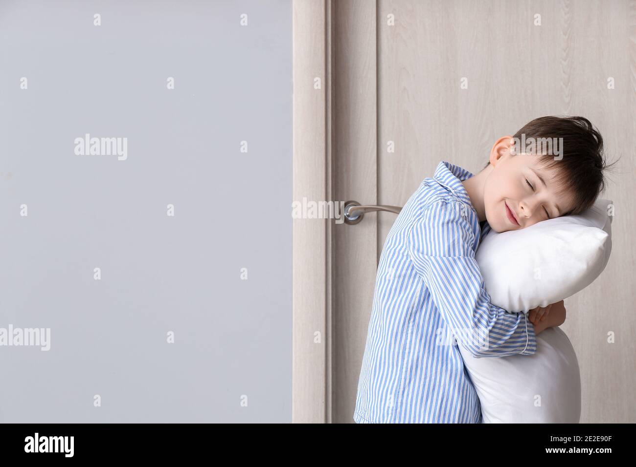 Sleepy little boy standing near closed door Stock Photo - Alamy