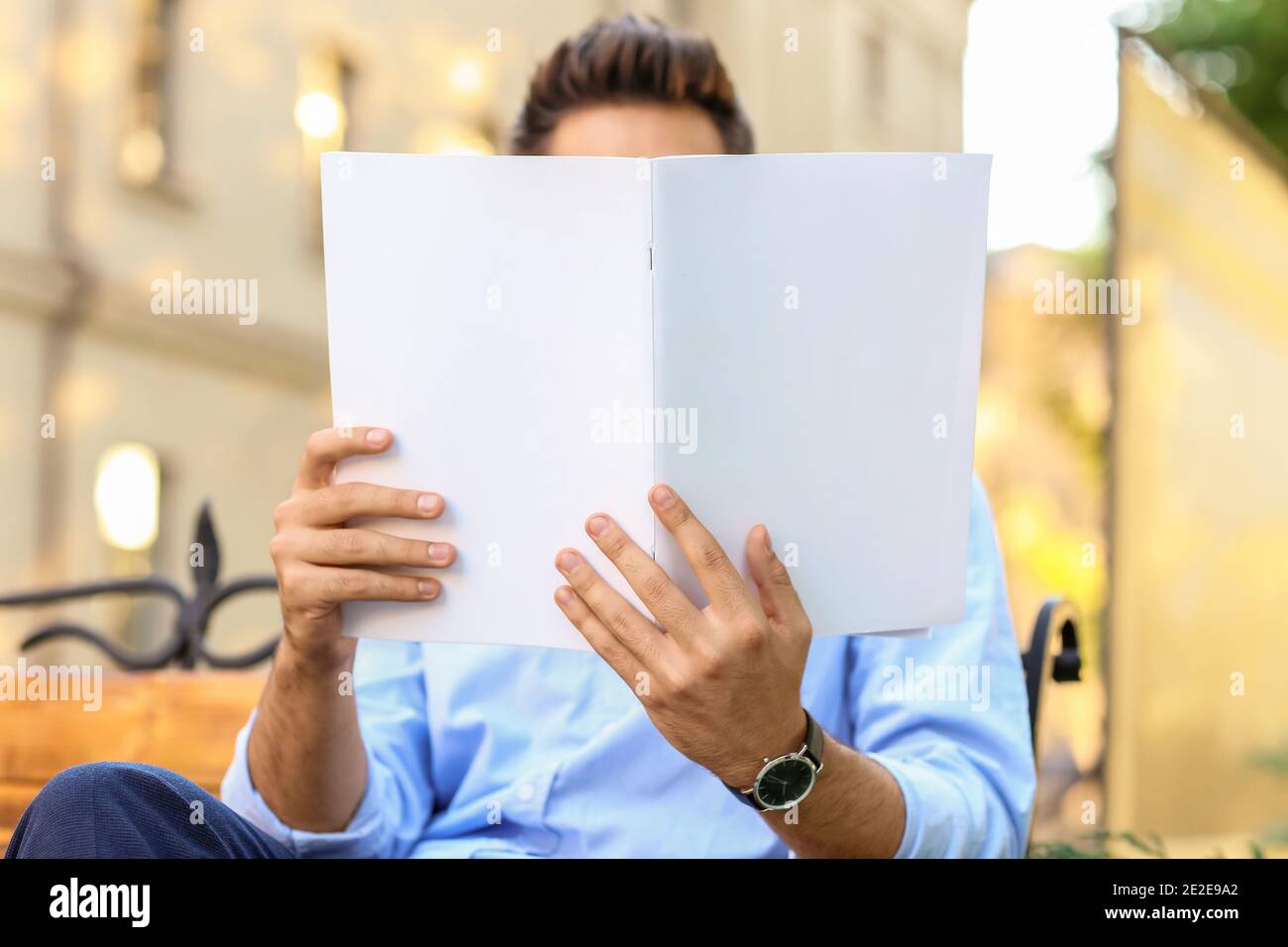 Young man reading magazine outdoors Stock Photo - Alamy