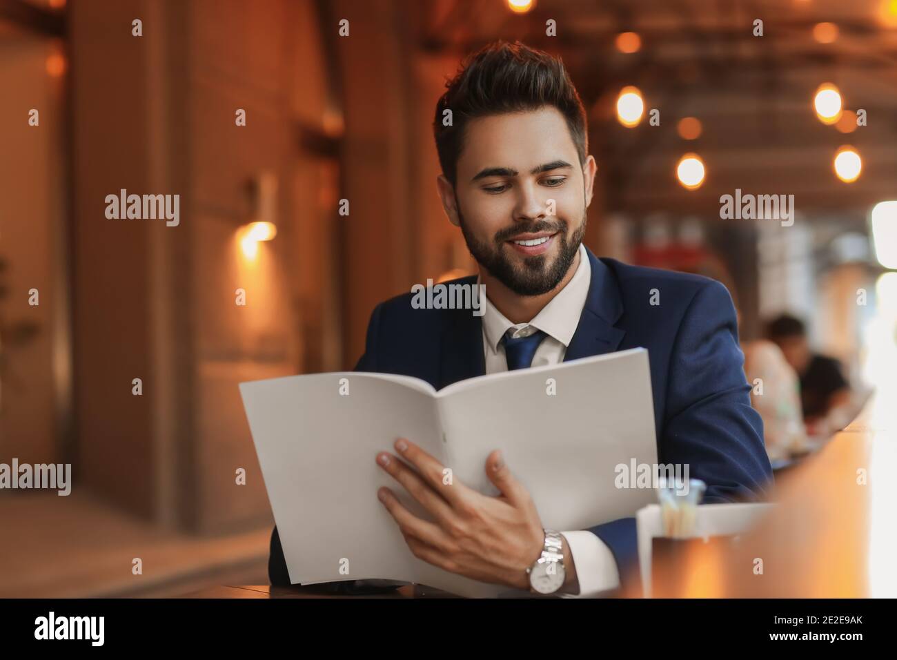 Young businessman reading magazine in cafe Stock Photo - Alamy