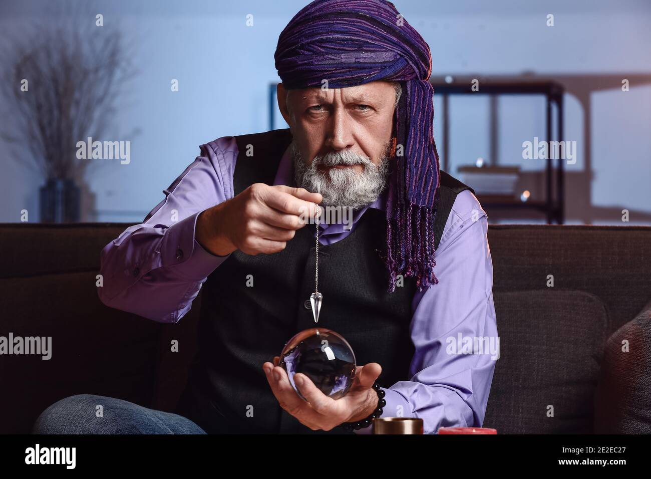Male fortune teller with crystal ball and pendulum at home Stock Photo ...