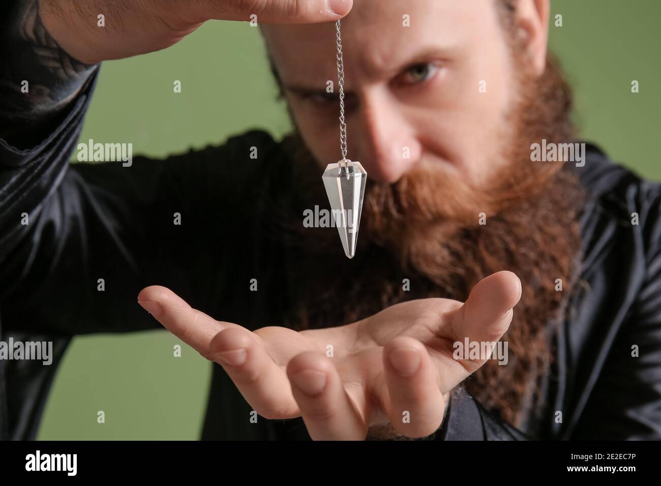 Male fortune teller with pendulum on color background Stock Photo - Alamy