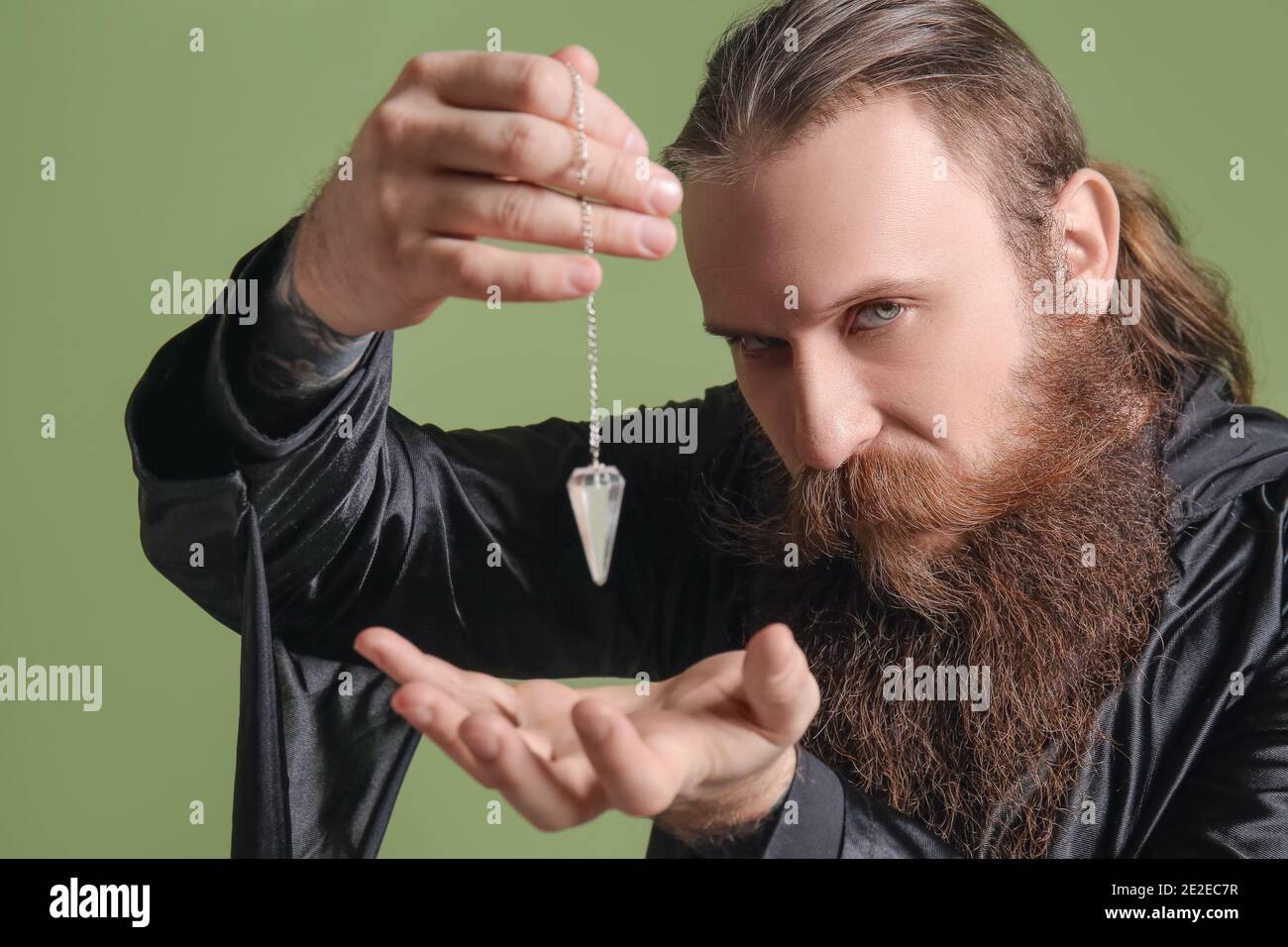 Male fortune teller with pendulum on color background Stock Photo - Alamy