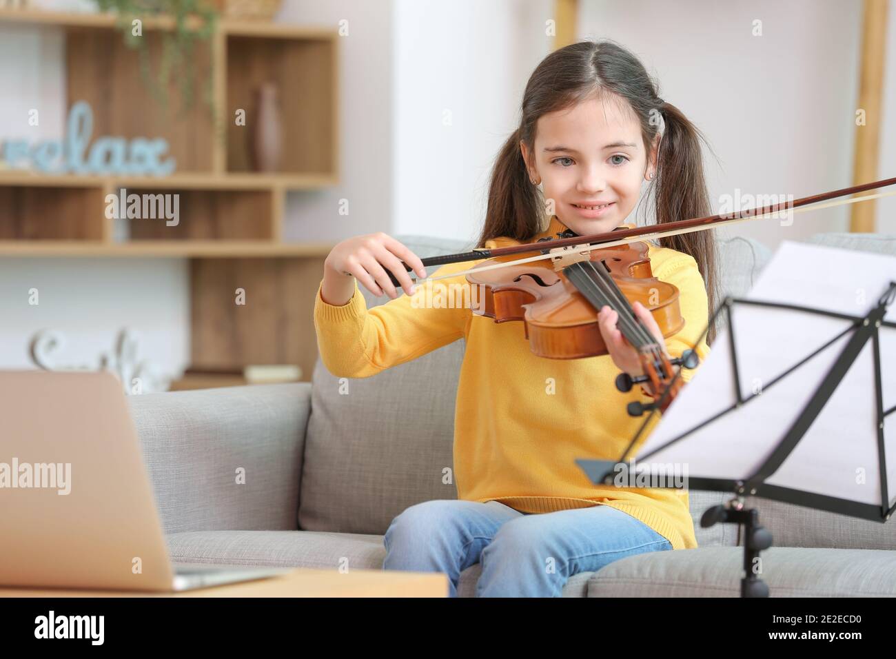 Little girl taking music lessons online at home Stock Photo - Alamy