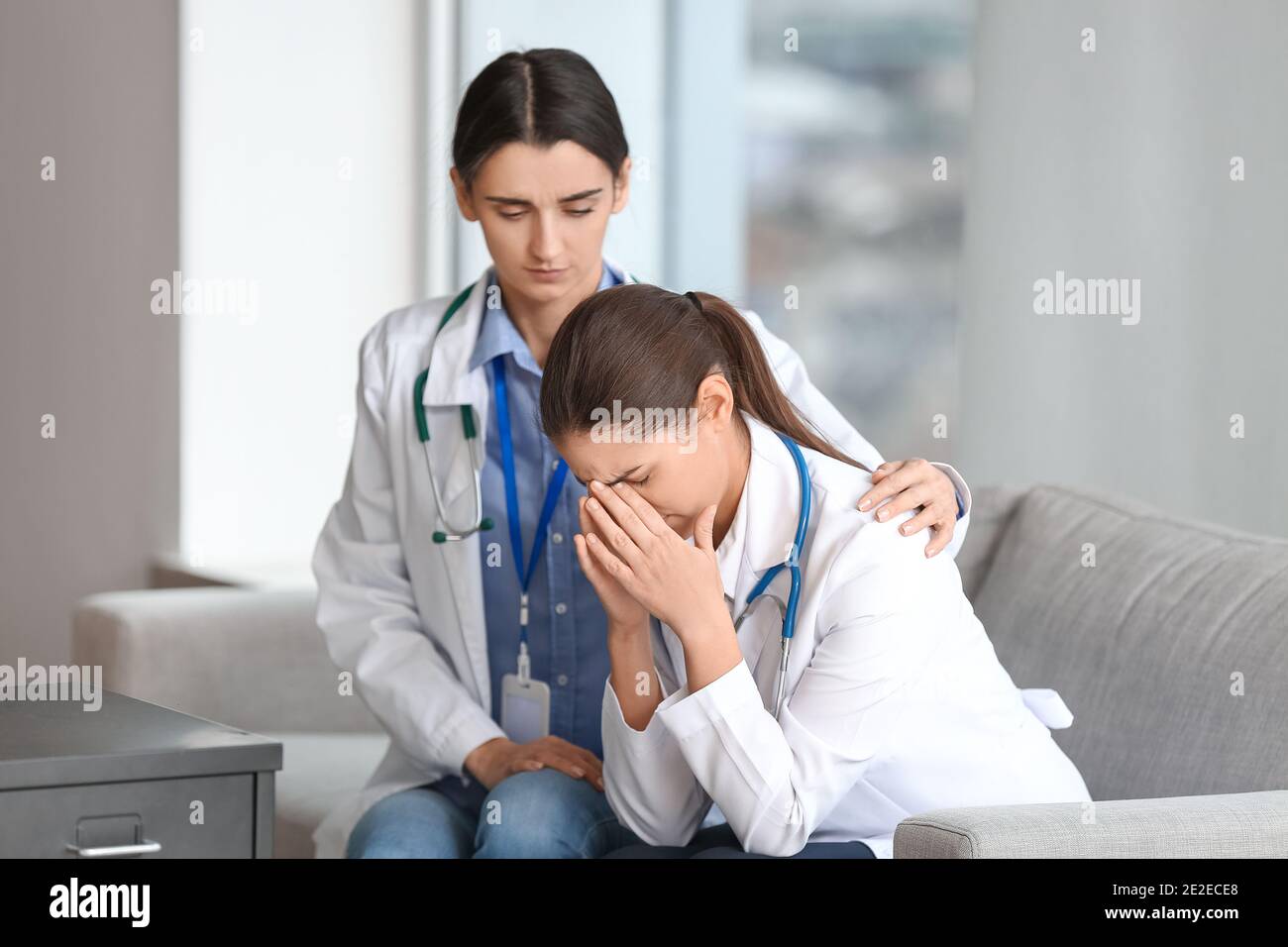 Female doctor calming her stressed colleague in clinic Stock Photo - Alamy