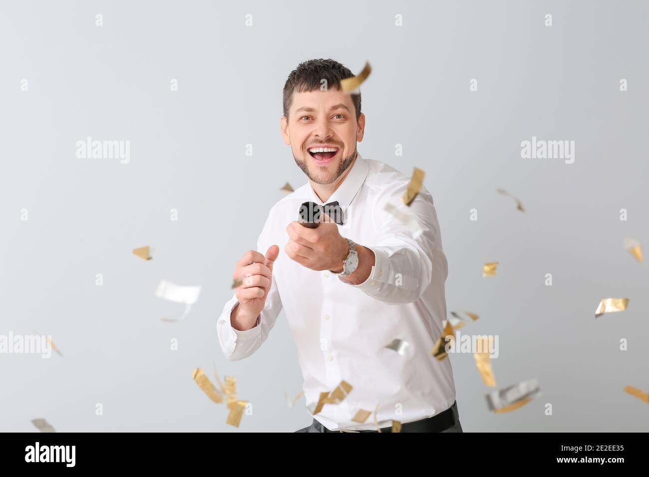 Happy man with noise maker and confetti on light background Stock Photo ...