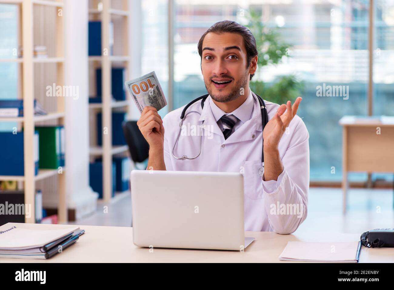 Young medic holding banknote in the clinic Stock Photo - Alamy