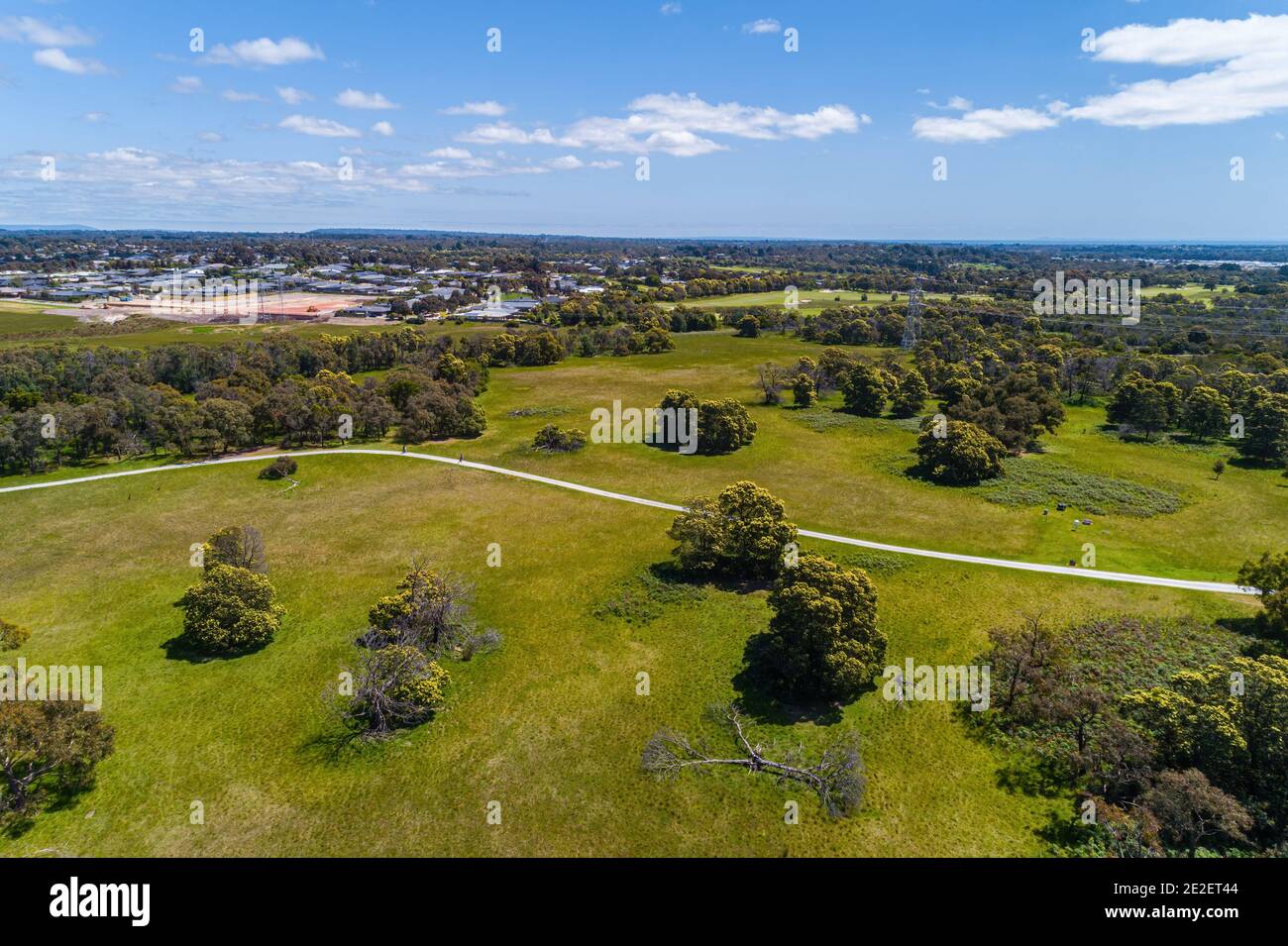 Aerial view of path through green grass and trees on bright sunny day ...